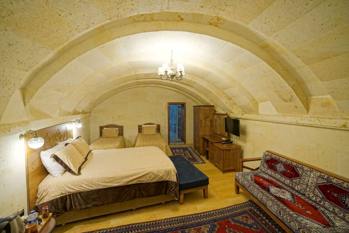 Quarto com uma cama grande, um sofá, uma televisão e um armário de madeira.