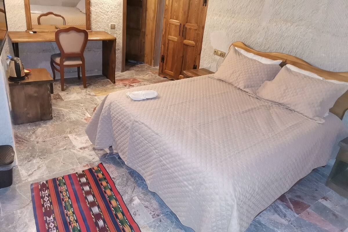 Um quarto com uma cama, uma escrivaninha, uma cadeira e um guarda-roupa.