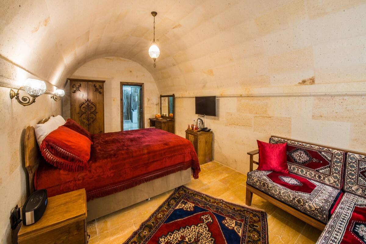 Um quarto aconchegante com uma cama grande, um sofá, uma TV e uma mesinha.
