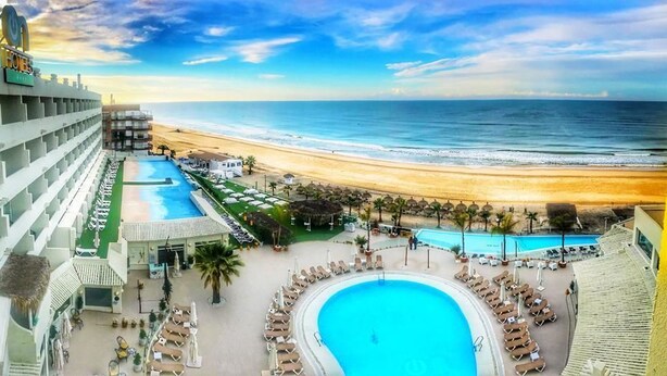 Hotel com piscina, praia e vista para o oceano.