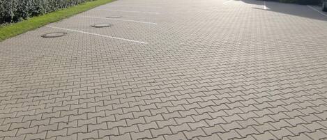 Uma área externa pavimentada com um caminho bem definido que leva à entrada de um edifício.