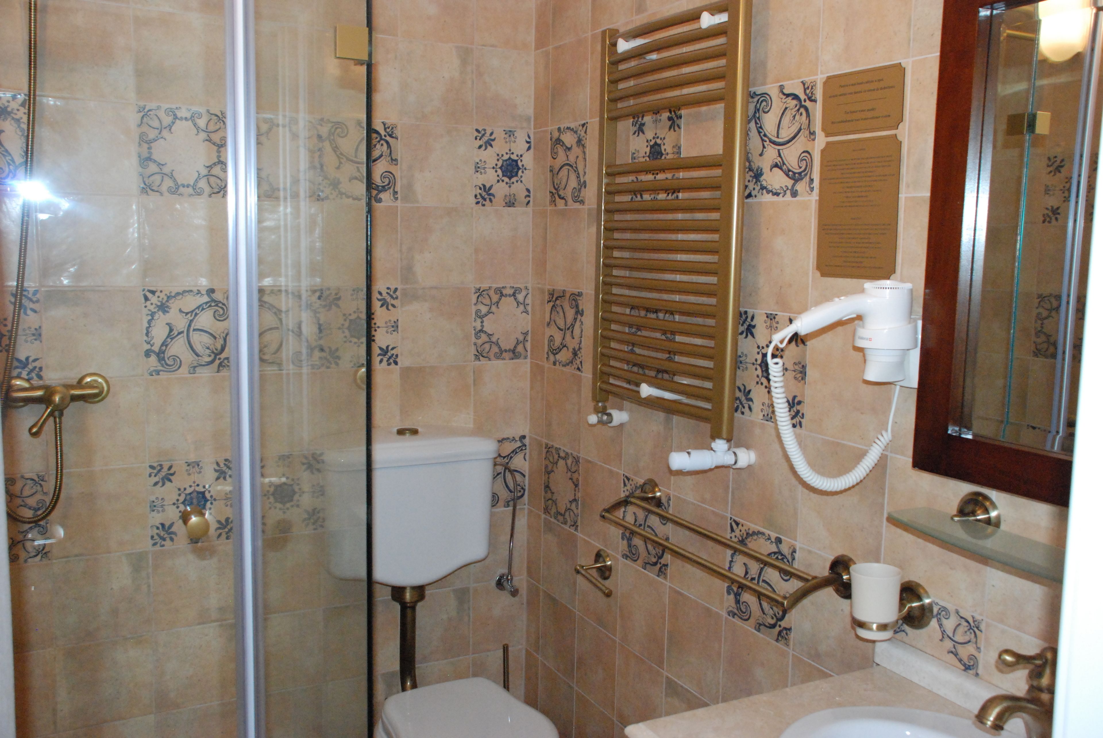 Uma casa de banho com cabine de duche em vidro, sanita, lavatório e suporte para toalhas.