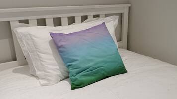 Cama com roupa de cama branca e almofada degradê.