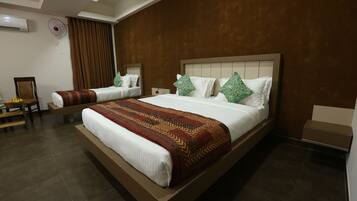 Quarto de hotel com cama grande, mesa de cabeceira, uma cadeira e um espelho.