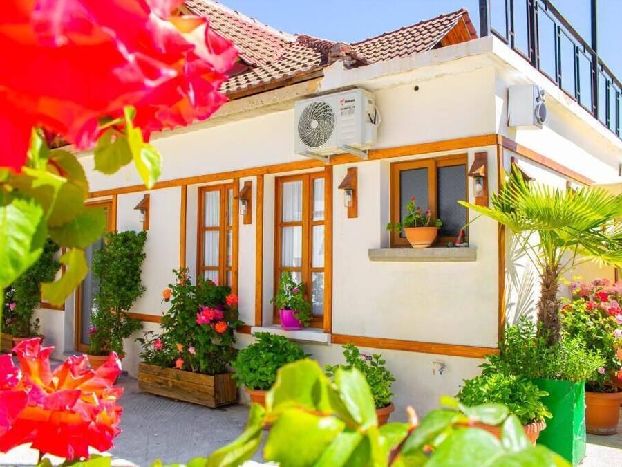 Um edifício com fachada branca, molduras de janela em madeira e telhado com telhas.