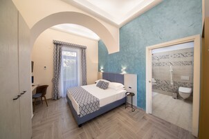 Quarto com cama, mesa de cabeceira e vista para o banheiro.