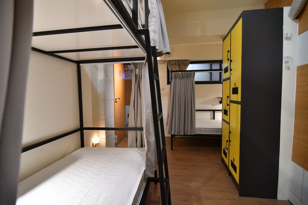 Quarto de dormitório com beliches, guarda-roupa e uma pequena mesa com abajur.