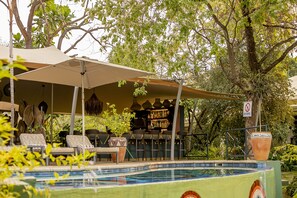 Uma área na piscina com espreguiçadeiras, um bar e um espaço coberto para sentar.