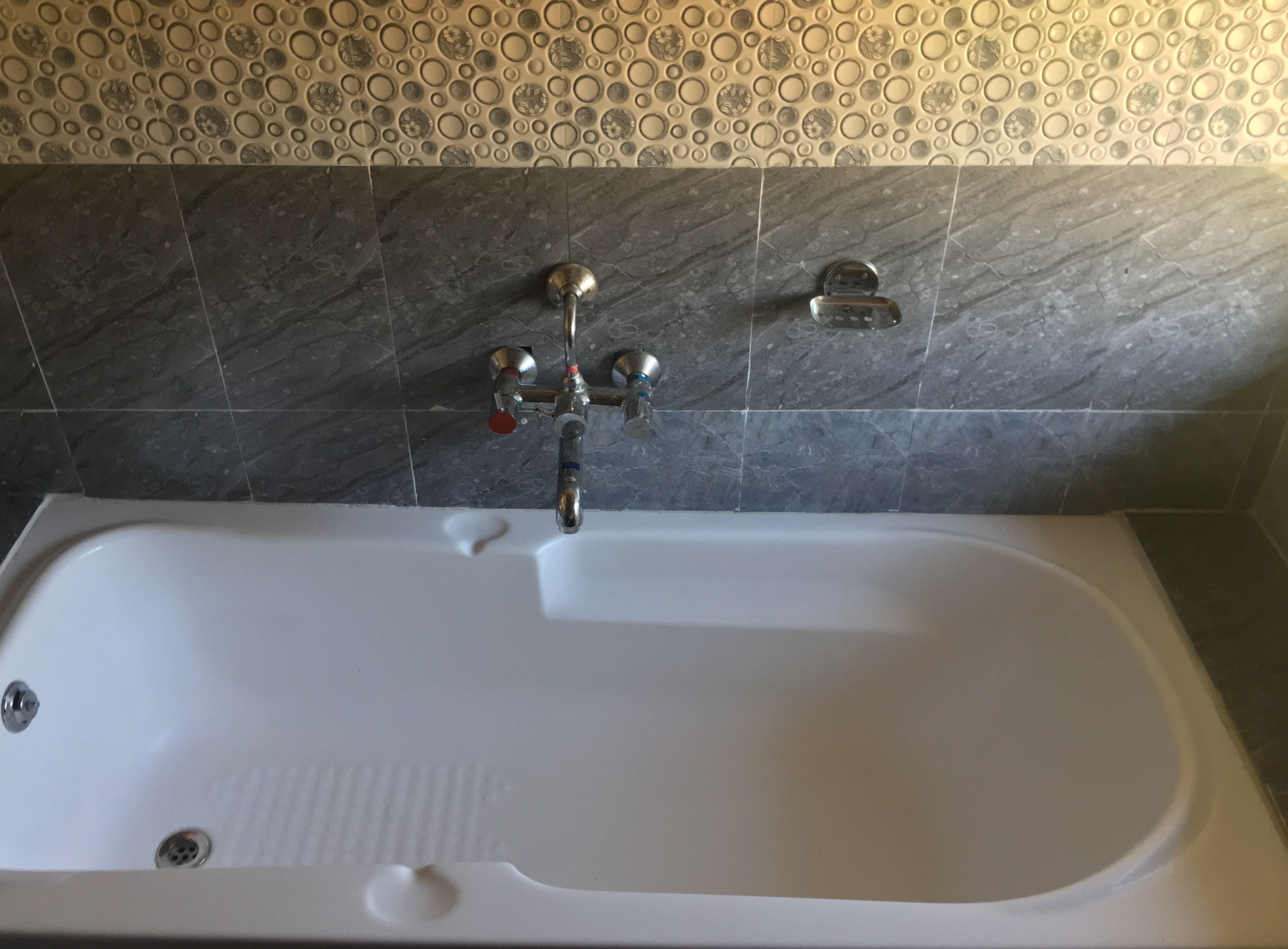 Uma banheira com uma torneira moderna e um chuveiro.