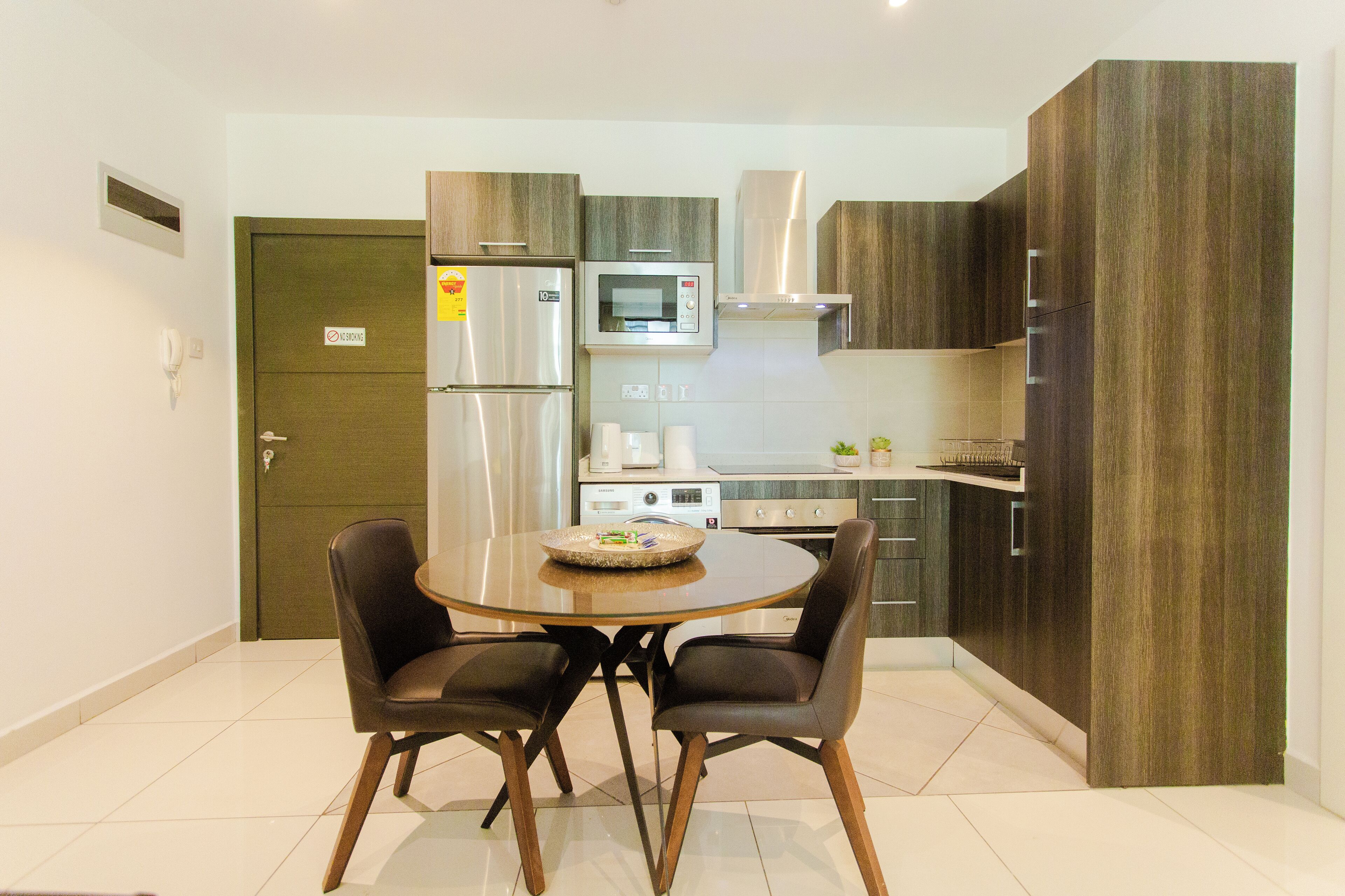 Uma cozinha moderna com mesa e cadeiras, geladeira, micro-ondas, fogão e armários de madeira.