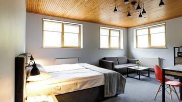 Quarto moderno com cama, escrivaninha e cadeira. Grandes janelas proporcionam luz natural.