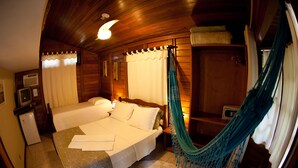 Um quarto aconchegante com cama, um pequeno frigorífico e uma rede.