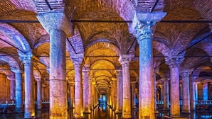 Um corredor longo com tetos altos e colunas, provavelmente parte de um edifício histórico.