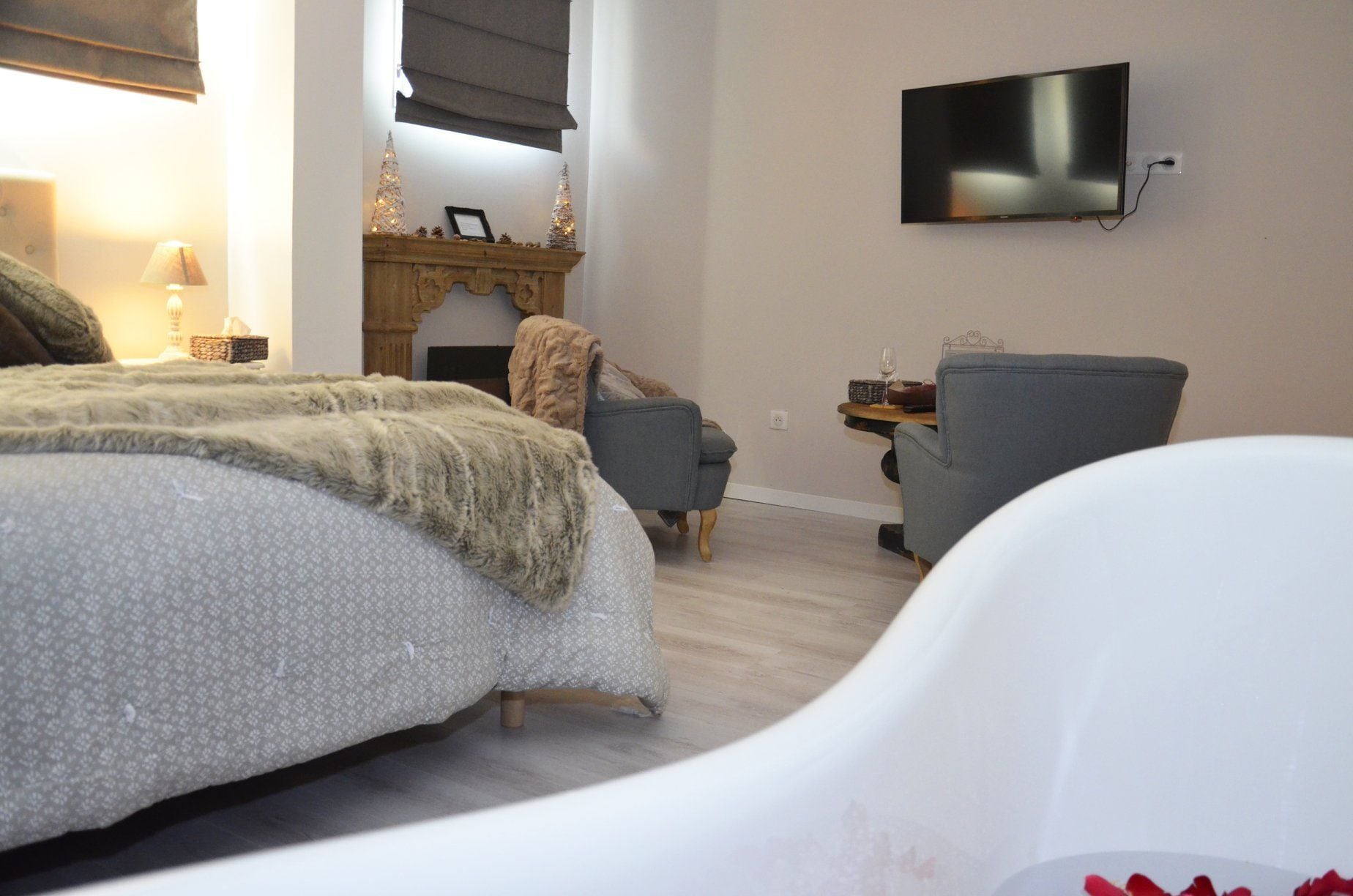 Quarto com cama, uma cadeira, televisão na parede e lareira.