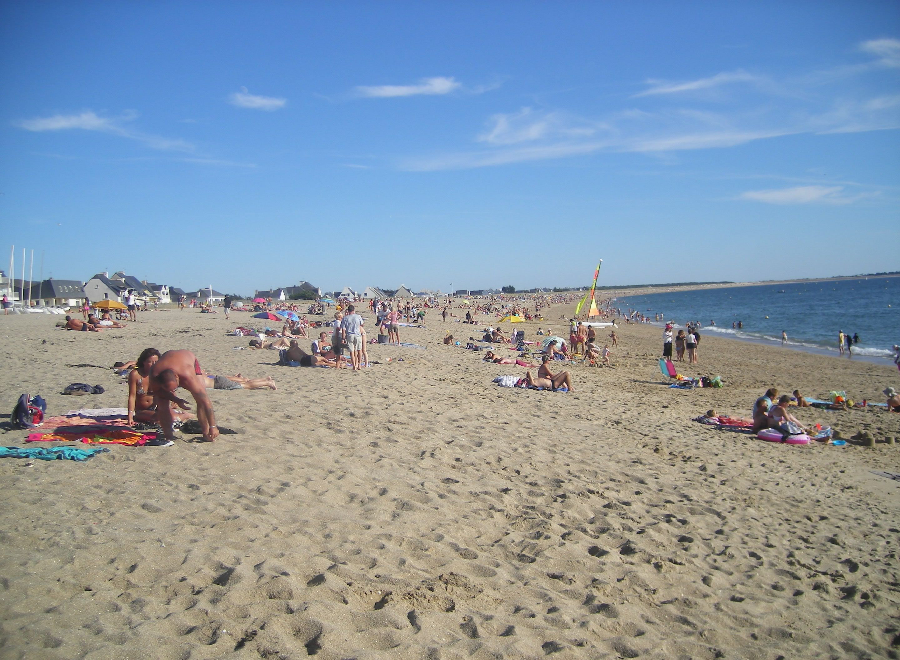 Uma praia cheia de gente tomando sol e nadando.