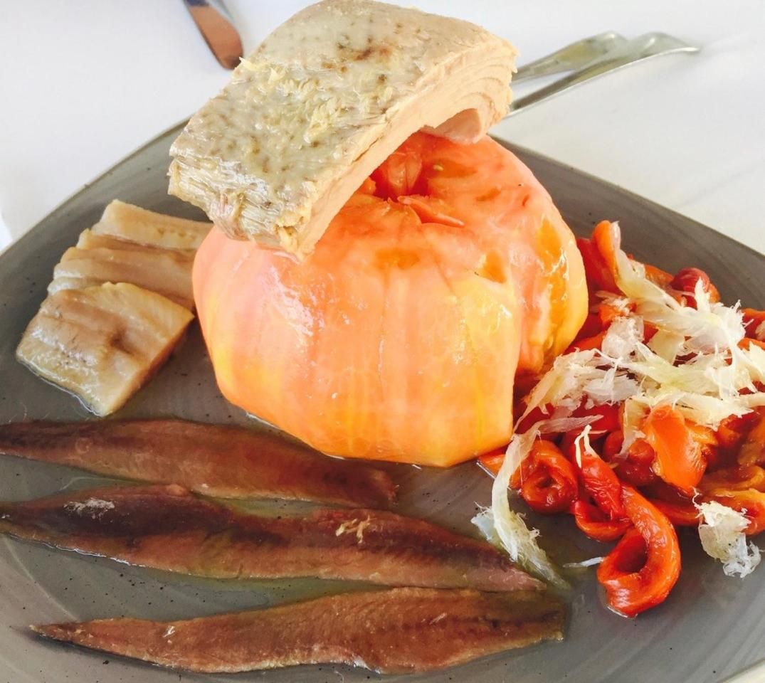 Um prato com peixe grelhado, abóbora recheada e acompanhamento de chucrute.