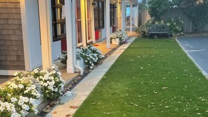 Um hotel com um gramado bem cuidado, uma galeria coberta e uma fileira de janelas.