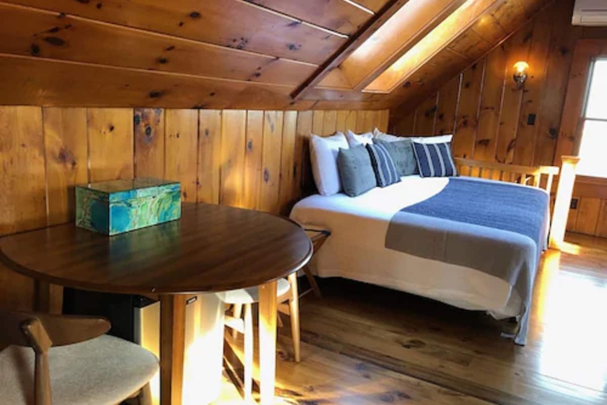 Quarto de cabana de madeira com cama, mesa e cadeira.