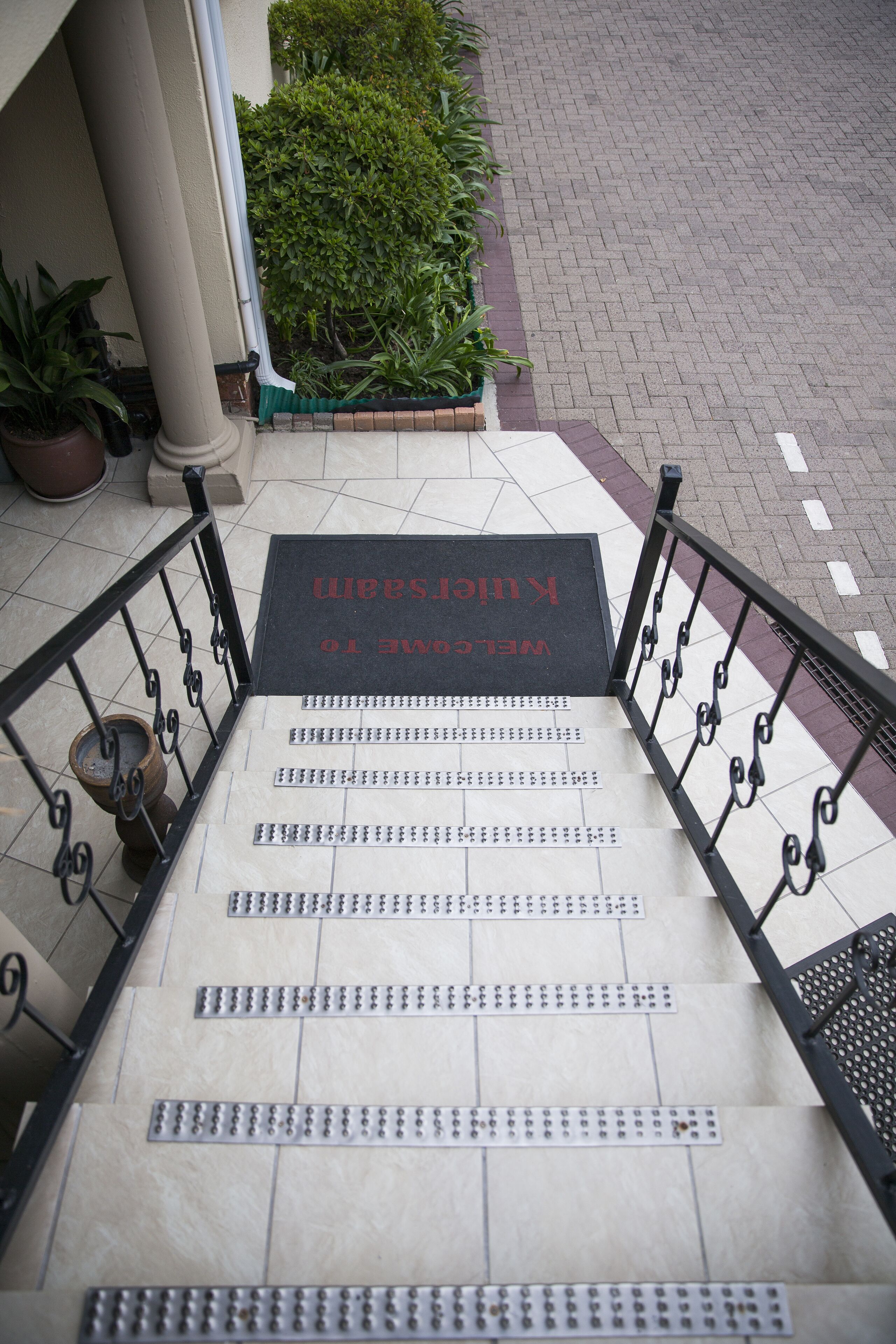 Escadaria com um tapete preto no topo com a inscrição 'Welcome to King & Queen Hotel'.