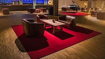Uma área de estar com sofás de couro, uma mesa de centro de madeira e um tapete vermelho.
