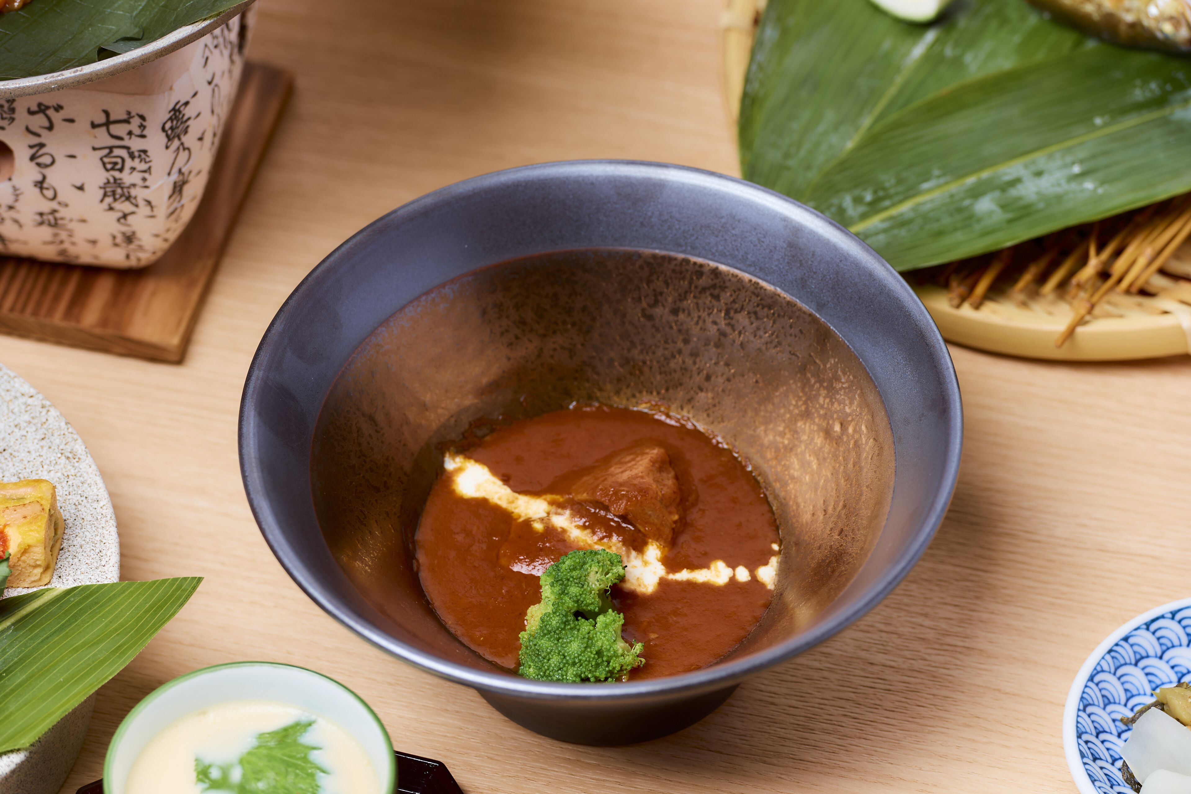 Uma tigela de sopa com enfeite sobre uma mesa de madeira.