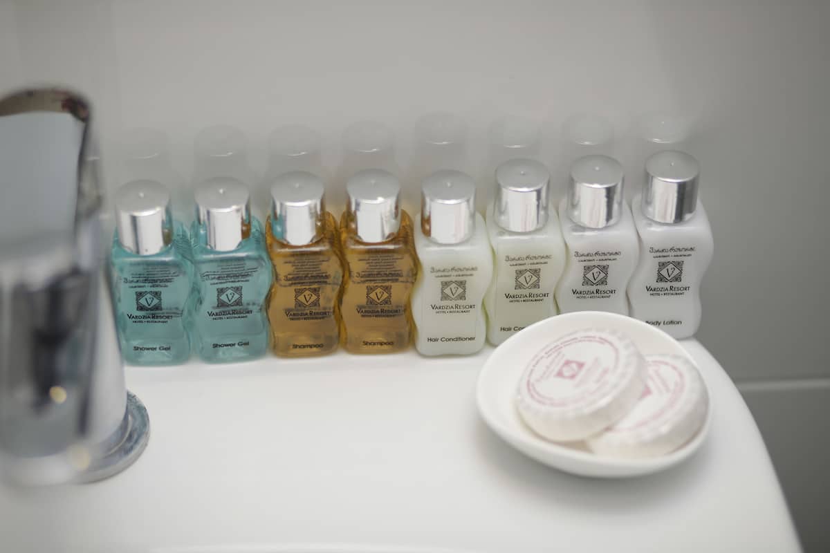 Uma seleção de produtos de higiene pessoal, incluindo gel de banho, shampoo e condicionador, com um prato de sabonetes.