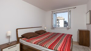 Quarto com cama, mesa de cabeceira, abajur, janela e armário de madeira.