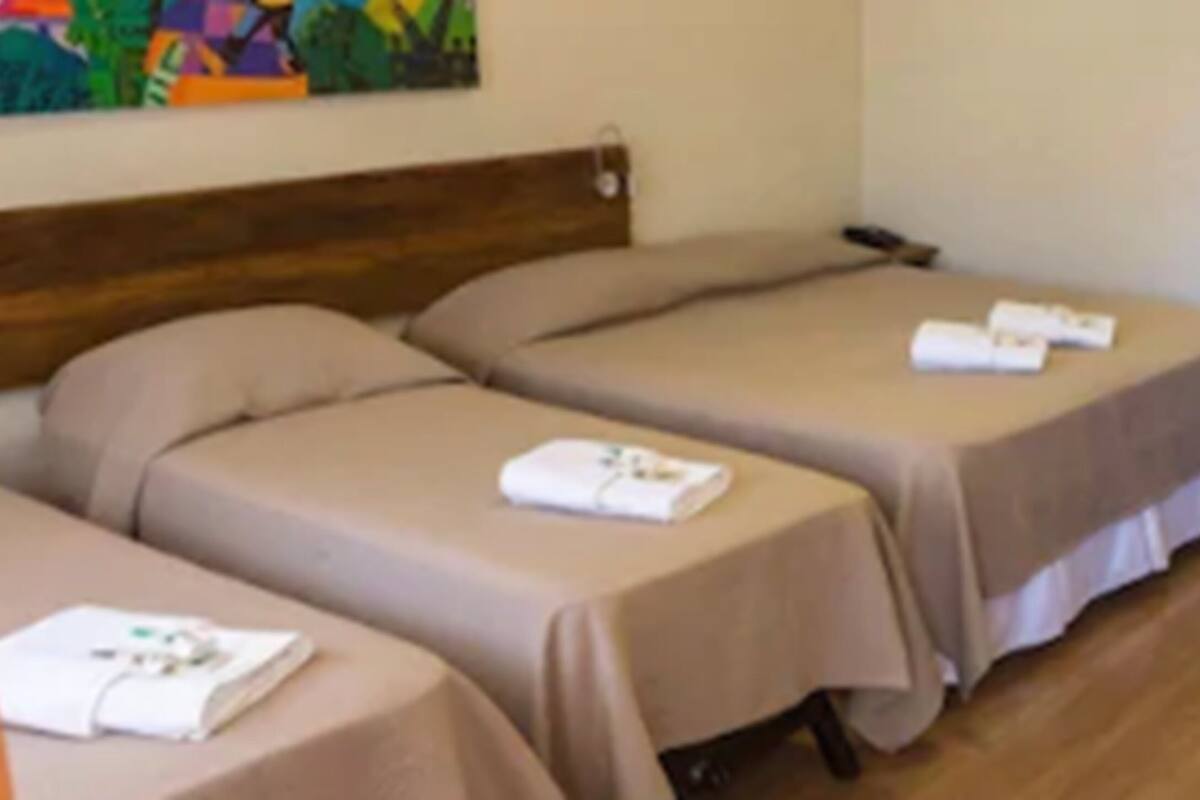 Quarto de hotel com duas camas, cada uma com uma toalha dobrada com cuidado.