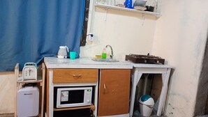 Uma cozinha compacta equipada com micro-ondas, torradeira, chaleira e pia.