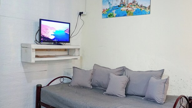 Um quarto com uma cama, uma televisão numa estante e um quadro na parede.