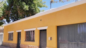 Um edifício amarelo com três janelas e uma porta de garagem.
