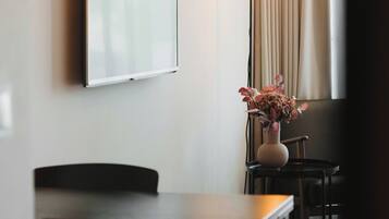Uma sala de jantar moderna com mesa, cadeiras, um vaso com flores e luminárias pendentes.