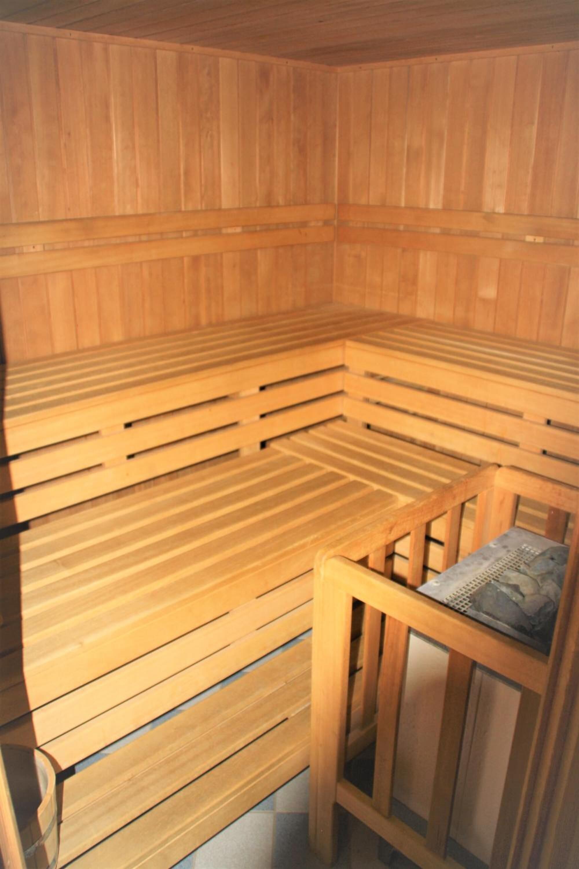 Uma sauna de madeira com bancos e uma pequena cadeira de madeira.