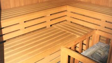 Uma sauna de madeira com bancos e uma pequena cadeira de madeira.