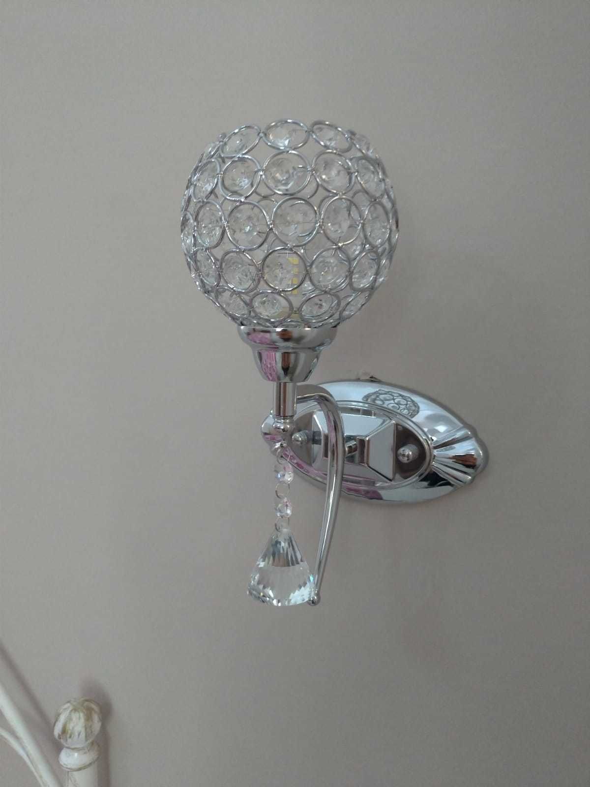 Uma luminária de parede com ornamento de vidro esférico e torneira cromada.