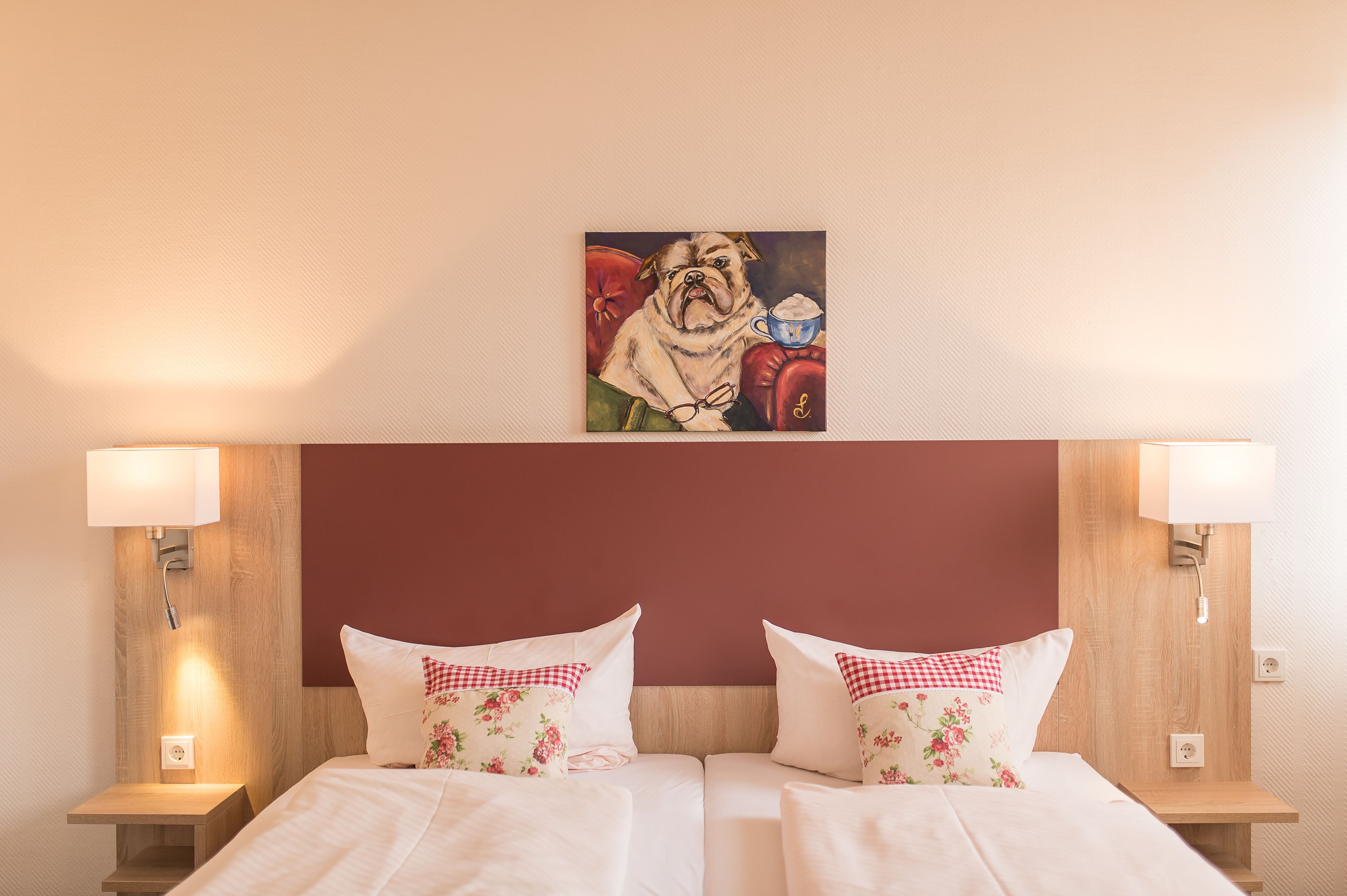 Quarto de hotel com uma cama, duas mesas de cabeceira, um quadro na parede e duas luminárias de parede.