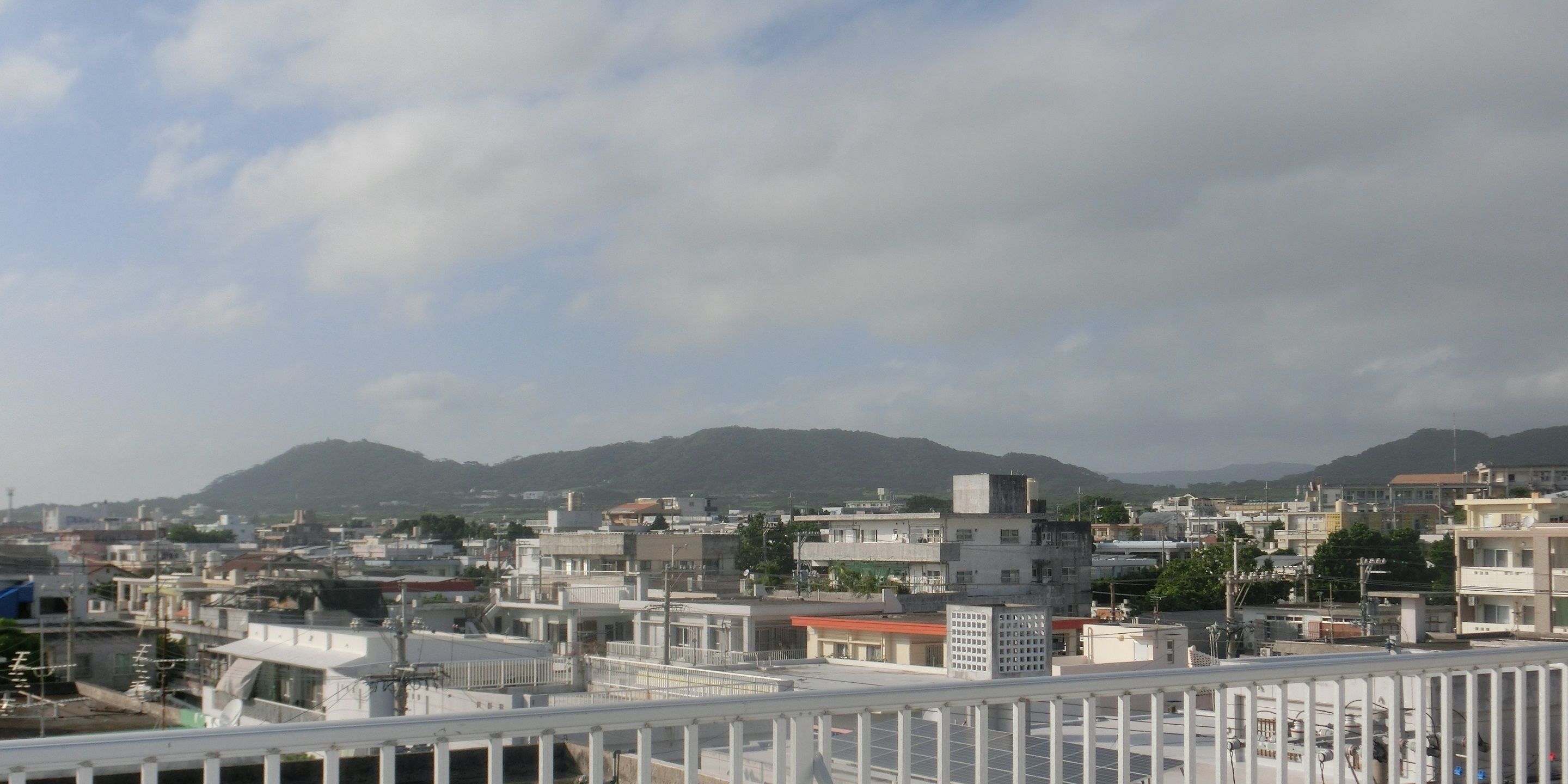 Paisagem urbana com edifícios e montanhas ao fundo.