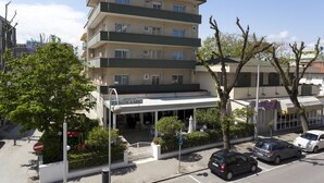 Hotel com vários andares, entrada coberta e área de estacionamento.