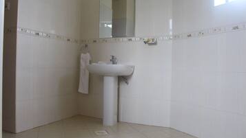 Casa de banho com lavatório branco, toalha pendurada num suporte e espelho sobre o lavatório.