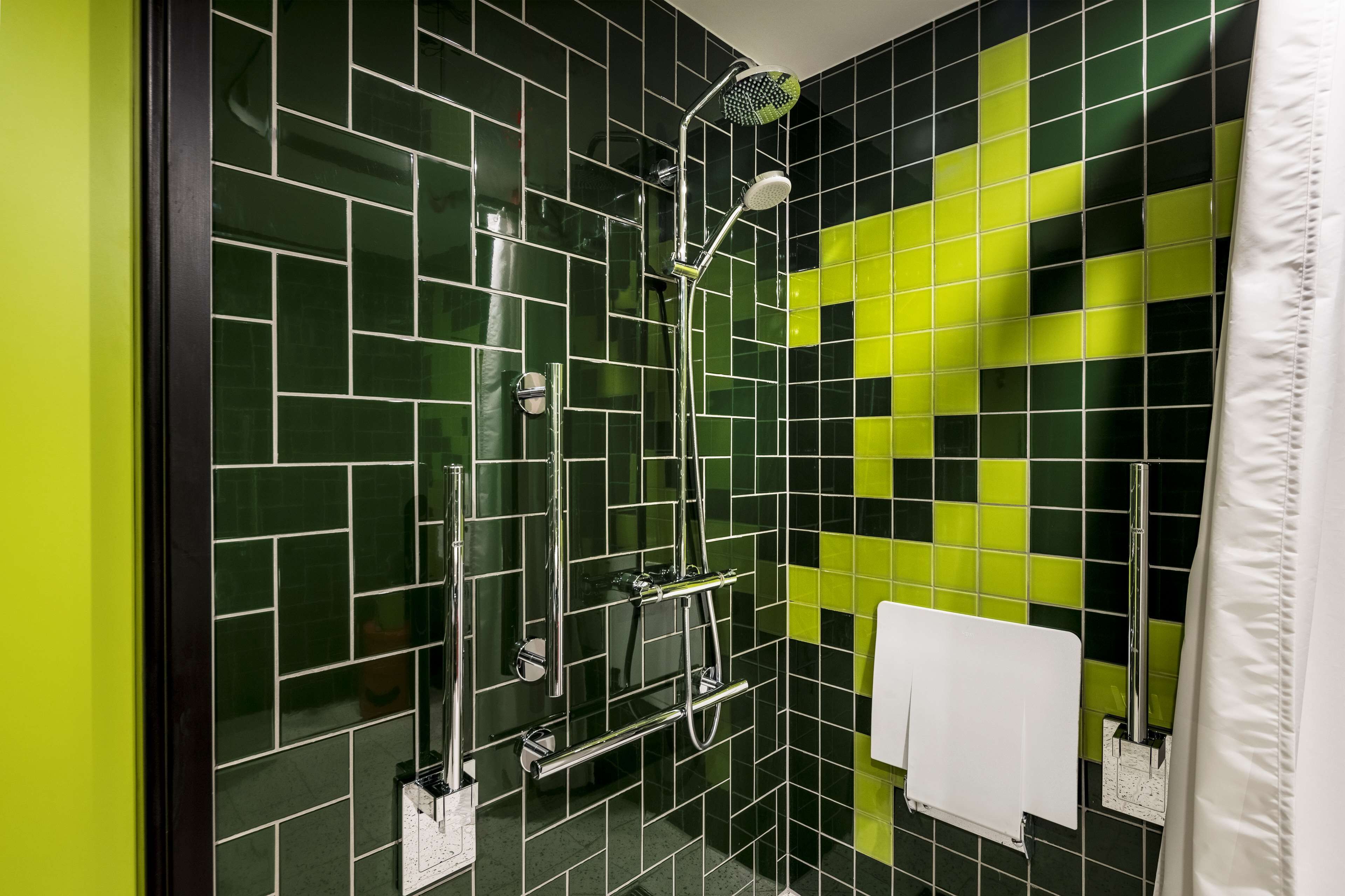Casa de banho com chuveiro, um porta-toalhas e um suporte para papel higiénico.