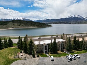 Um edifício com estacionamento e vista para um lago e montanhas.