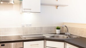 Uma cozinha moderna com uma pia de aço inoxidável, fogão embutido e armários brancos.