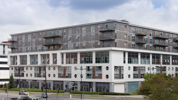 Um edifício com vários andares e design arquitetônico moderno, com varandas e grandes janelas.