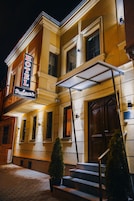 Um hotel com fachada de tijolos, entrada coberta e placa de identificação.