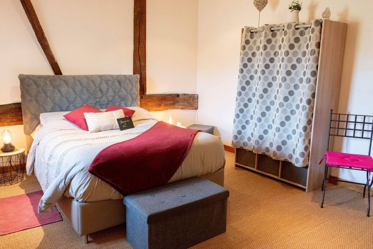 Quarto com cama, mesa de cabeceira e uma cadeira.