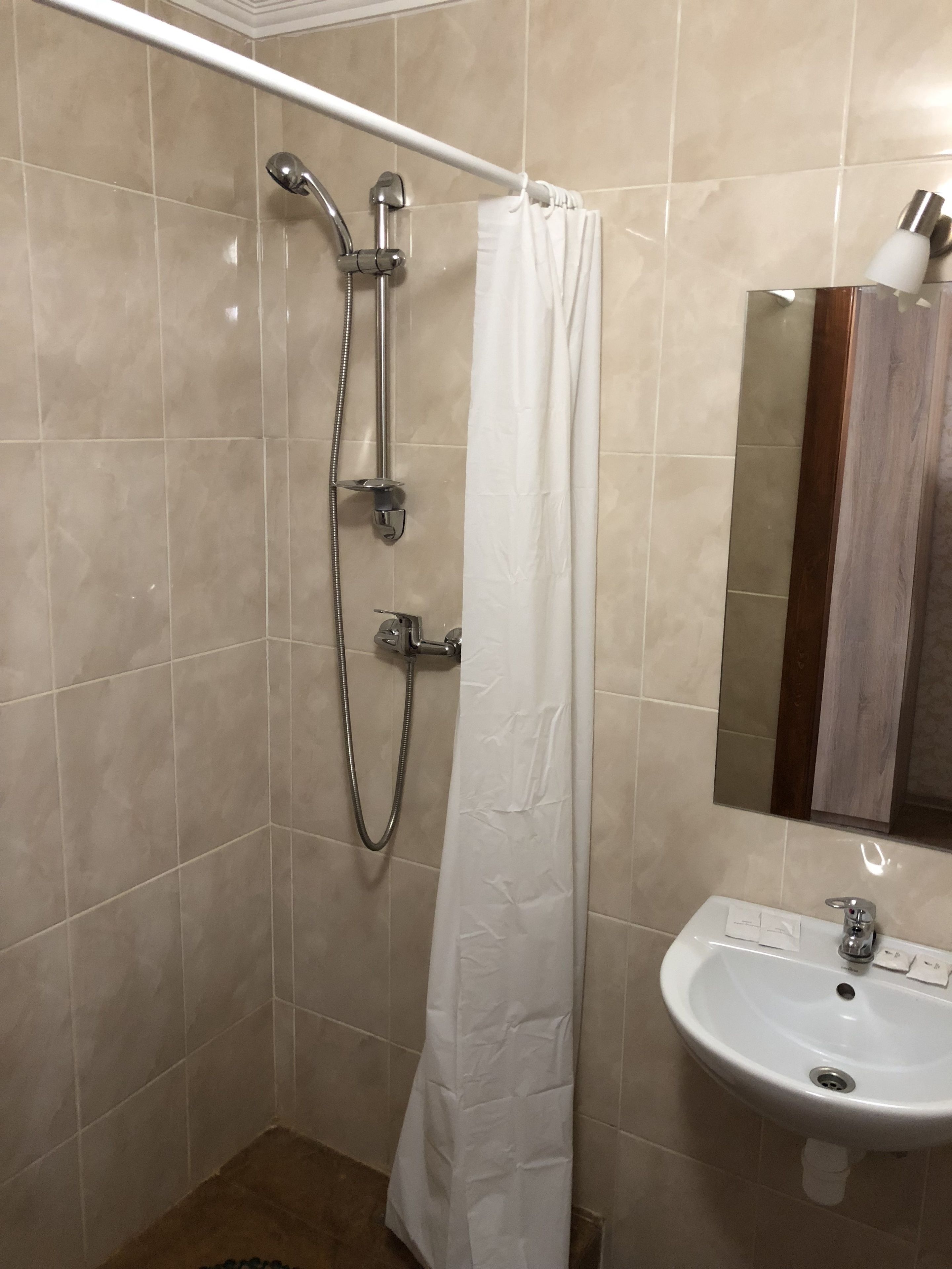Casa de banho com chuveiro, lavatório e espelho.