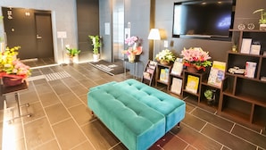 Um hall moderno com um sofá verde-água, uma TV de tela plana e diversas plantas e flores.