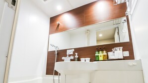 Uma casa de banho moderna com uma pia branca, um espelho em cima e um chuveiro.
