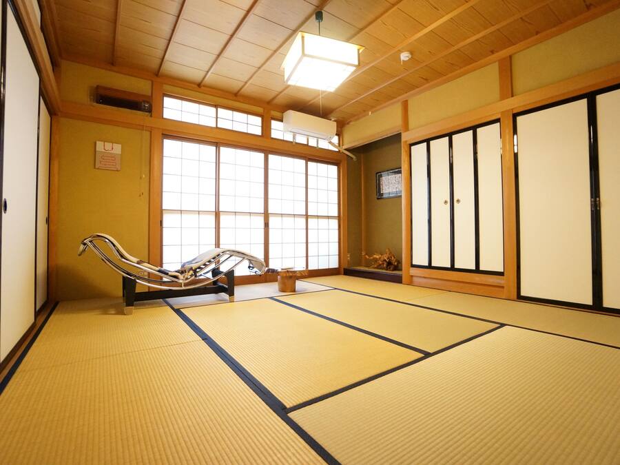 Um quarto japonês tradicional com tatames, portas deslizantes e esteira de tatame pendurada.