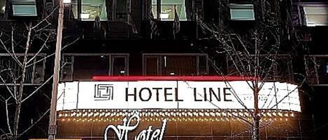 Um edifício de hotel com vários andares e uma placa grande com a inscrição 'HOTEL LINE' na entrada.